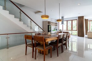 Cozinha moderna com uma mesa de jantar de madeira, cadeiras e escada de vidro.