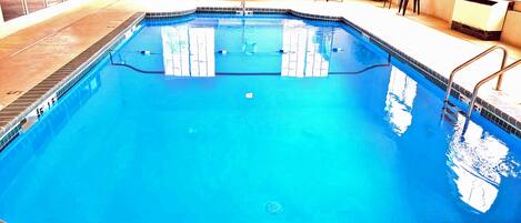 Piscina interna com água cristalina, um boi salva-vidas e uma placa indicando a profundidade da piscina.