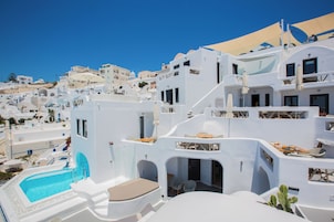 Um edifício branco com piscina e área externa para sentar.