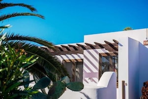 Um edifício moderno com fachada branca, porta de vidro e estrutura de pérgola.