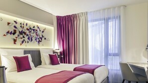 Quarto de hotel com cama, duas mesas de cabeceira, escrivaninha e uma cadeira.