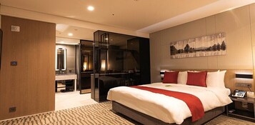 Quarto de hotel com uma cama grande, uma escrivaninha com cadeira, um espelho e um quadro na parede.