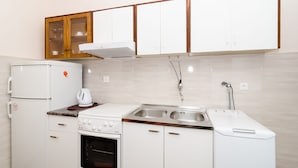 Uma cozinha compacta com geladeira, fogão, forno, pia e micro-ondas.