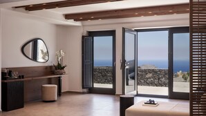 Casa de banho moderna com um espelho grande, um banco e vista para o mar através de portas abertas.