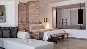 Quarto moderno com cama, mesa de cabeceira, banqueta e um espelho grande.