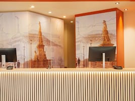 Balcão de recepção com um grande mural de um edifício histórico e uma estátua.