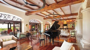 Uma sala de estar espaçosa com um piano de cauda, assentos confortáveis e vista para o exterior.
