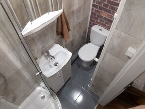 Casa de banho compacta com lavatório branco, sanita e zona de duche.
