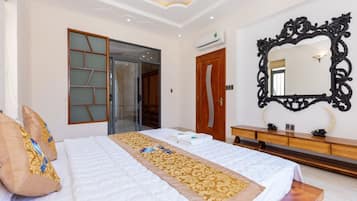 Quarto de hotel com uma cama grande, cómoda de madeira, espelho e porta de correr para um banheiro.