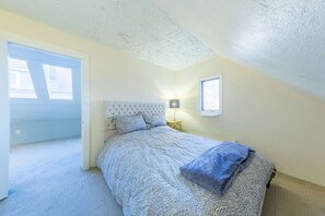Quarto com cama, mesa de cabeceira, luminária e janela.
