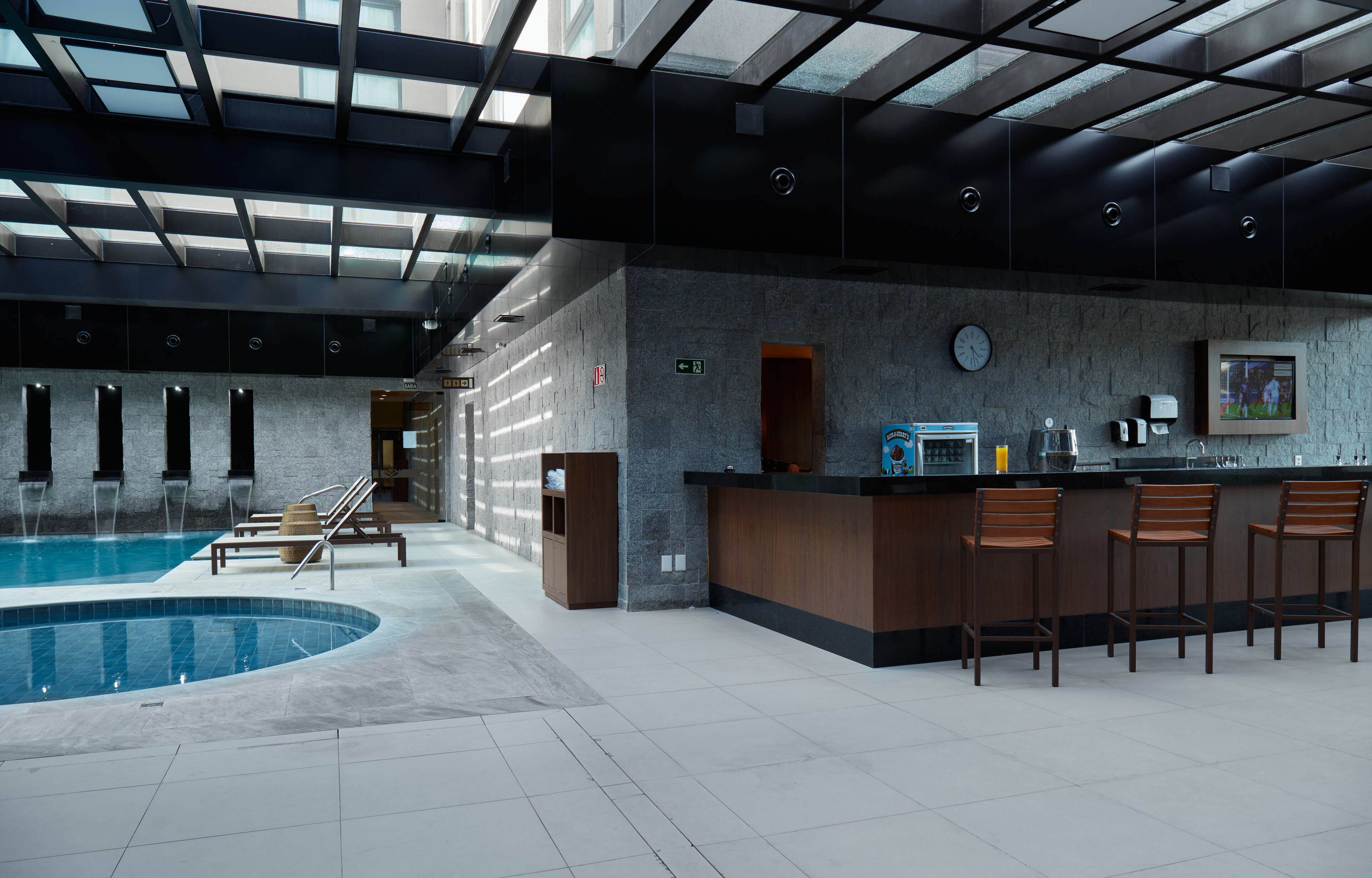Uma área de piscina interior moderna com bar e assentos.