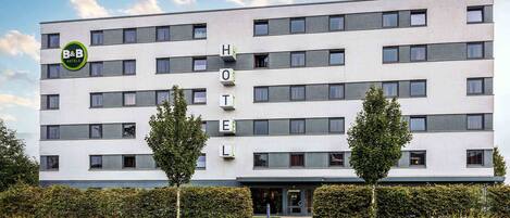 Um hotel moderno com fachada plana, várias janelas e uma placa indicando ser um hotel B&B.