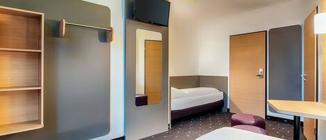 Quarto de hotel moderno com cama, escrivaninha, espelho e televisão.