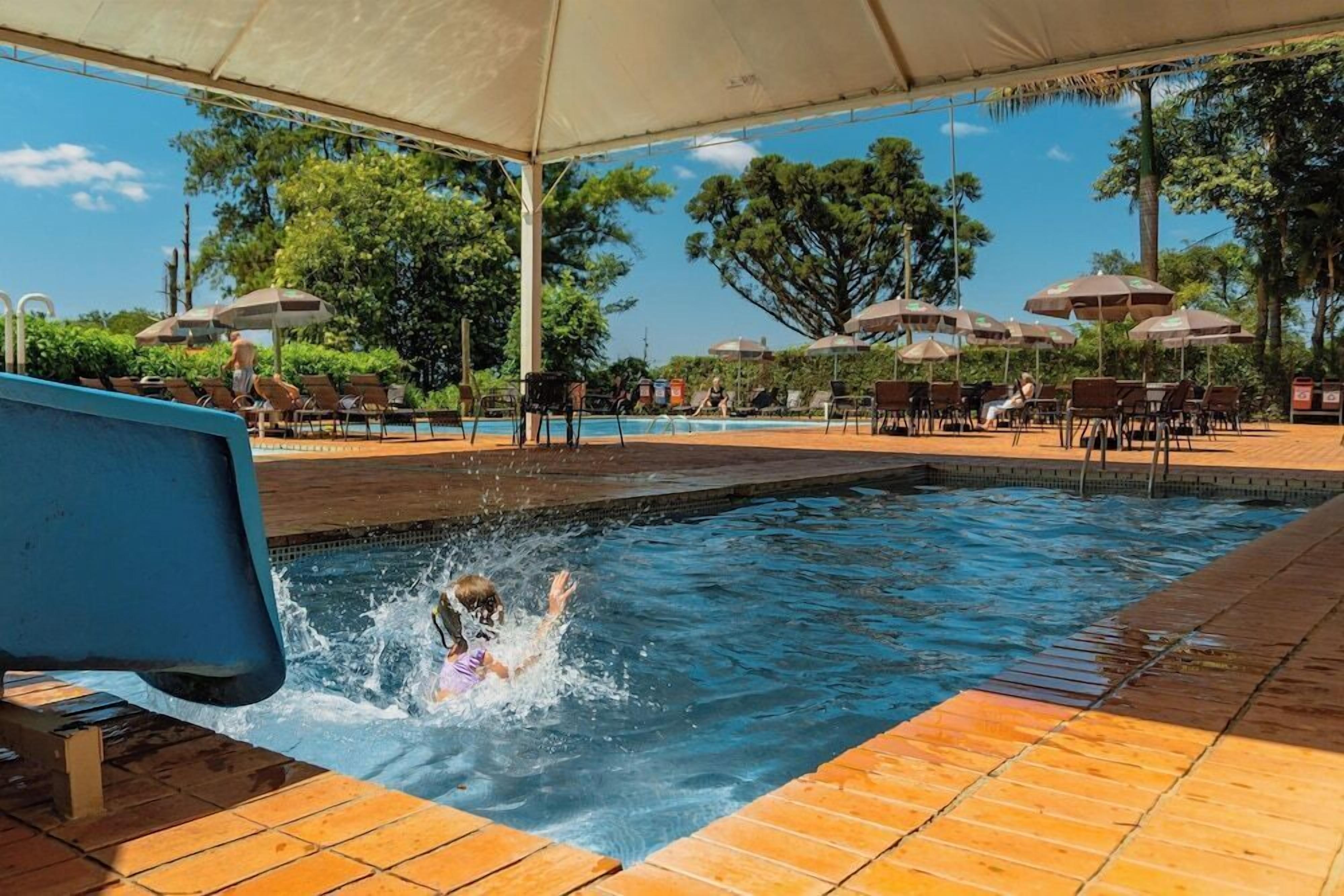Uma área de piscina com espaço de estar coberto e guarda-sóis.