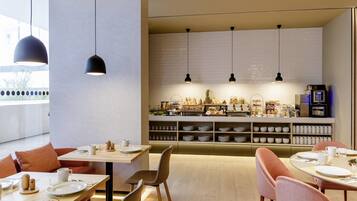 Uma área de jantar moderna com mesas, cadeiras e um balcão de buffet com comida e bebidas.