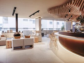 Uma área de bar moderna com balcão curvo, banquetas de madeira e teto alto com luminárias de design exclusivo.