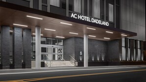 Exterior do AC Hotel Dadeland com design moderno, apresentando uma entrada marcante com portas de vidro e uma escadaria que leva à recepção.