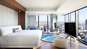 Quarto moderno com uma cama grande, vista para a cidade e televisão de tela plana.