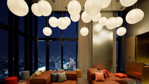 Uma sala de estar moderna com grandes janelas, um conjunto de sofá e luminárias esféricas pendentes.