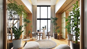 Um interior moderno com grandes janelas, piso de madeira e várias plantas em vasos.