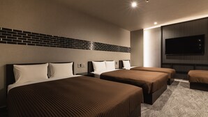 Quarto de hotel com três camas, televisão de tela plana e design moderno.