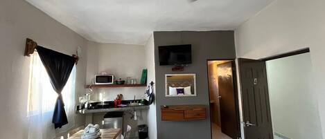 Cozinha compacta com micro-ondas, pia e área de refeições com mesa e cadeiras.