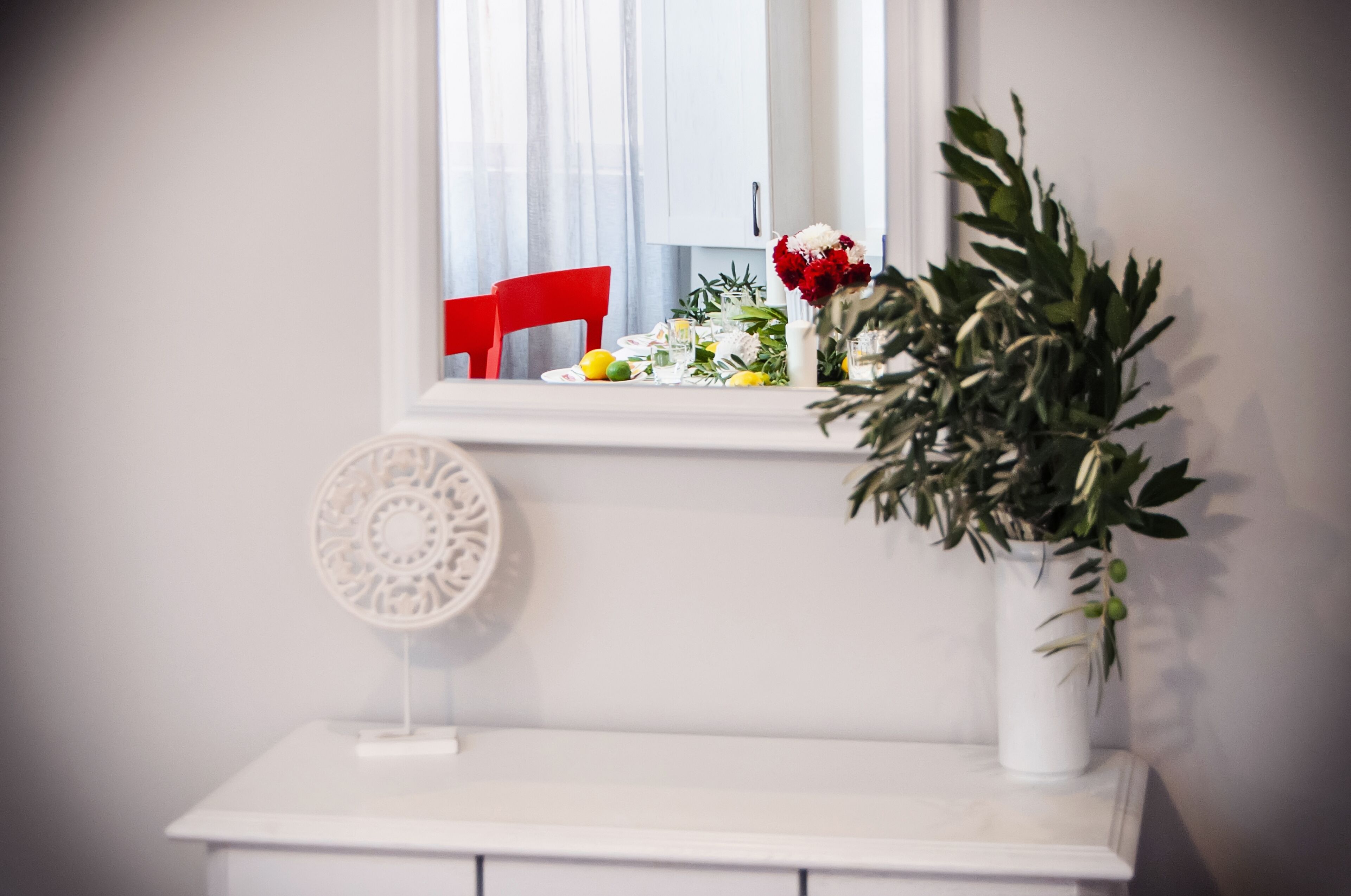 Uma mesa branca com um prato decorativo e um vaso de planta.