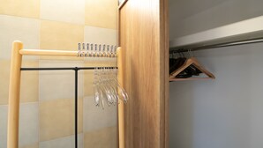 Casa de banho com cabine de duche em madeira, um porta-toalhas com várias toalhas e uma estante para pendurar roupa em madeira.