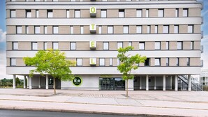 Um hotel moderno com fachada plana, vários andares e área de recepção no nível térreo.