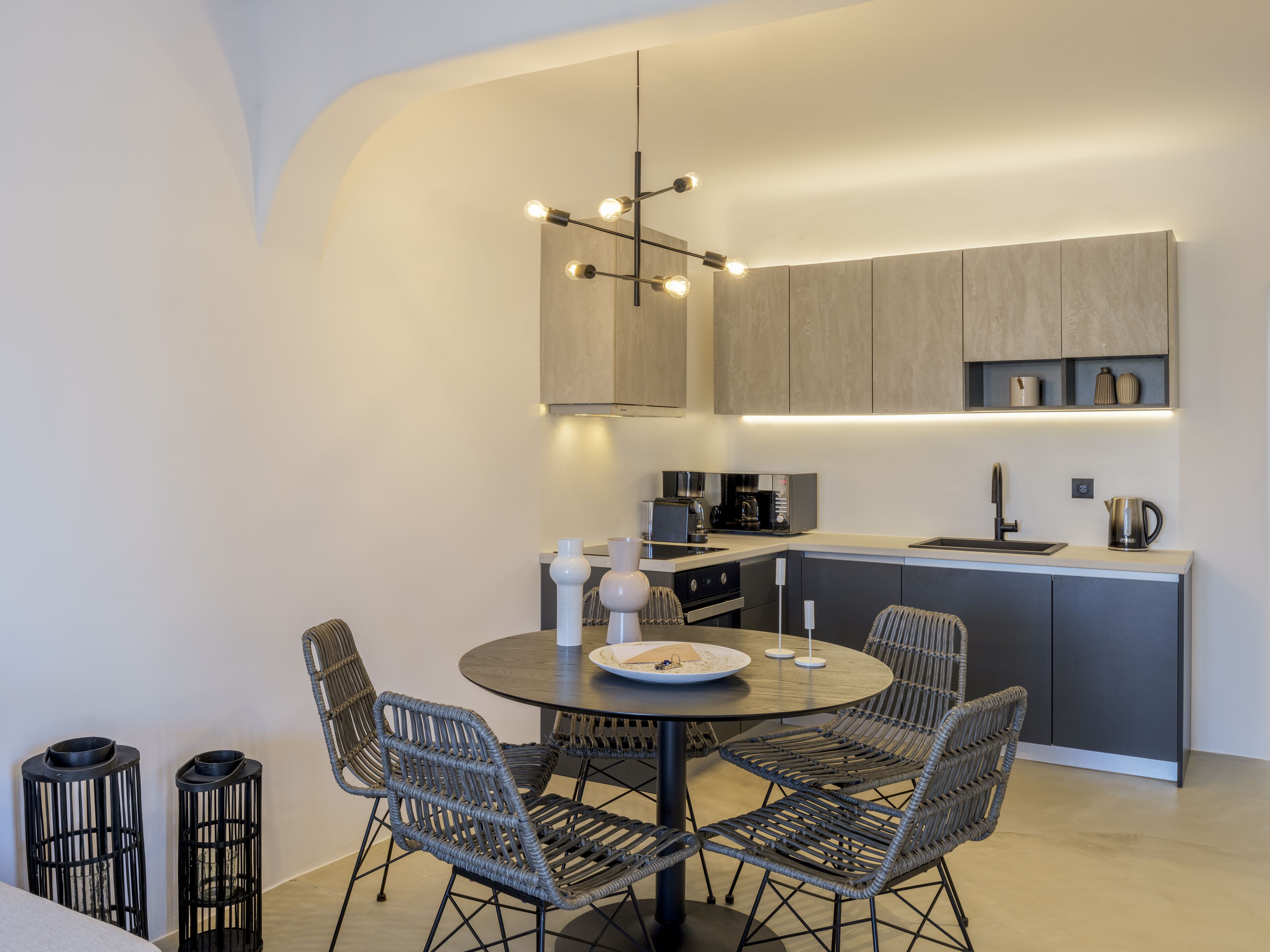 Cozinha moderna com mesa de jantar redonda, cadeiras de vime e armários embutidos.