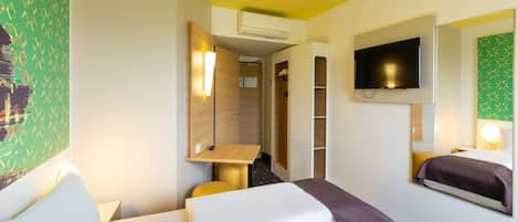 Quarto de hotel com duas camas, televisão, espelho e guarda-roupa.