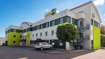 Um hotel tipo bed and breakfast com design moderno, com estacionamento e um carro estacionado na frente.