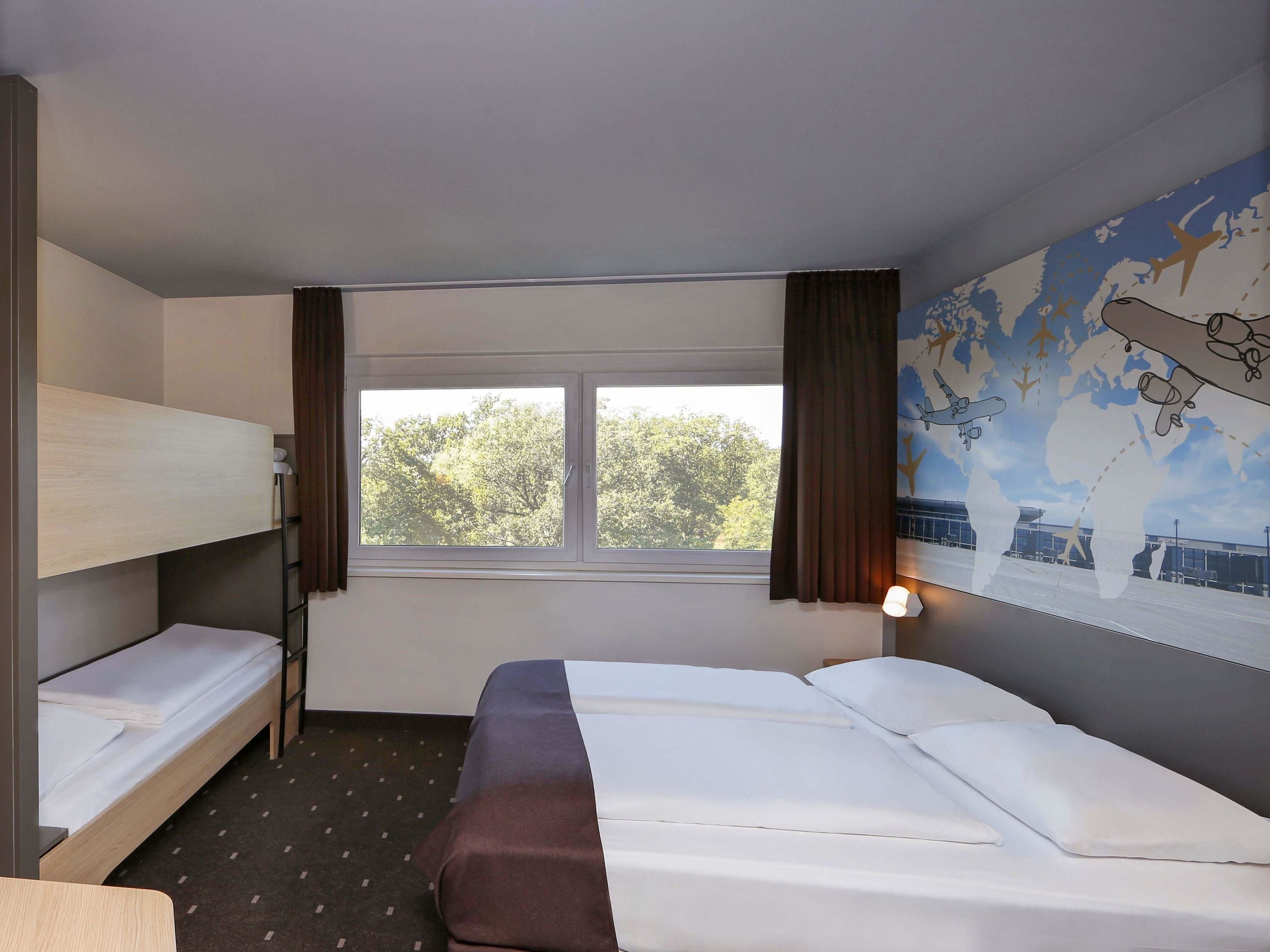 Quarto de hotel com cama de solteiro, uma cama individual, janela com cortinas, mapa na parede e luminária.