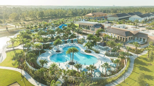 Resort com piscina central, vários edifícios e vegetação ao redor.