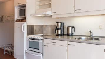 Cozinha compacta com forno embutido, micro-ondas e cafeteira.