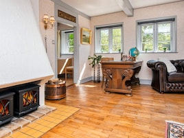 Sala de estar com lareira, piso de madeira, sofá de couro e mesa de jantar.