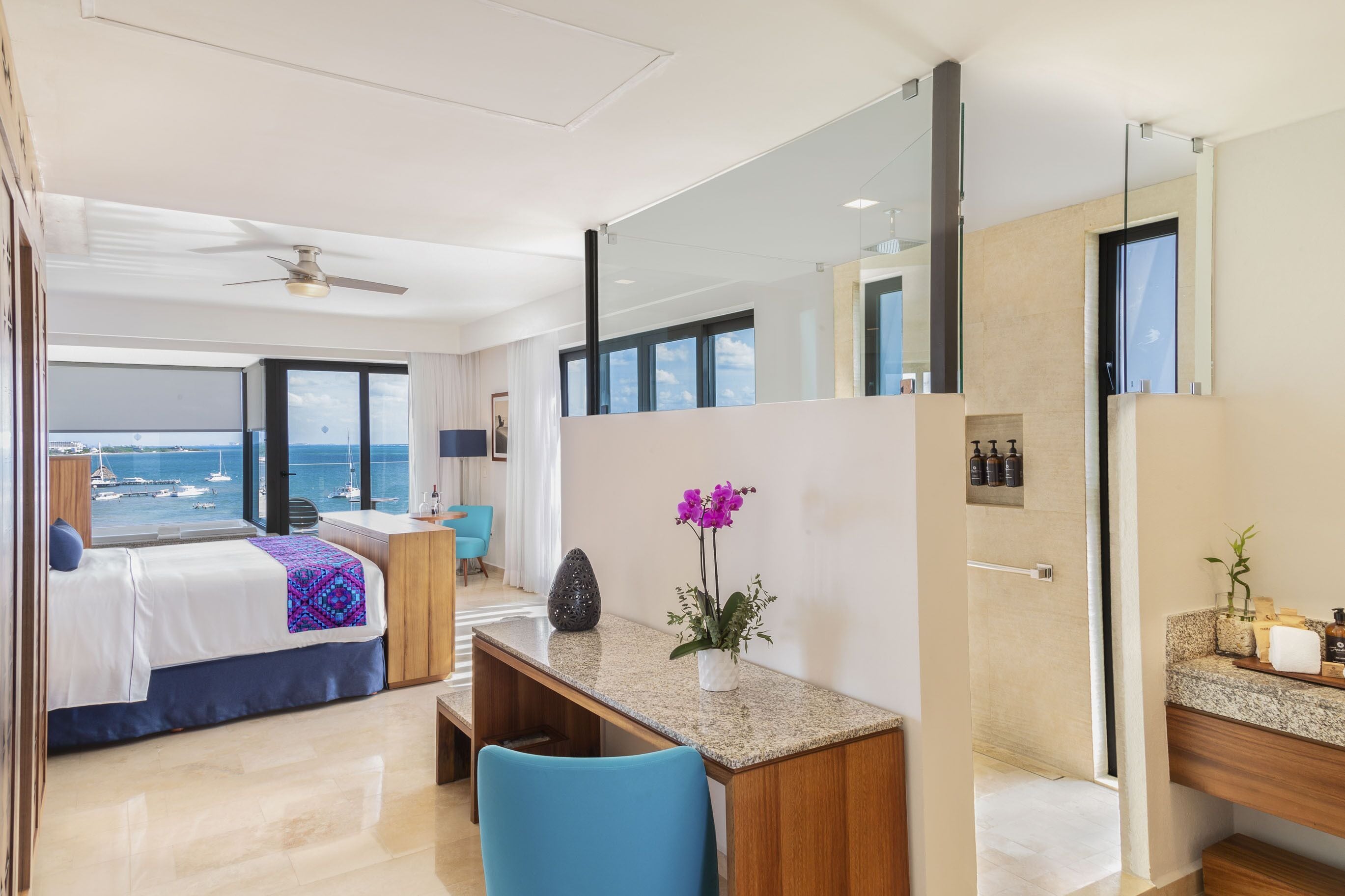 Quarto de hotel moderno com cama, escrivaninha e banheiro.