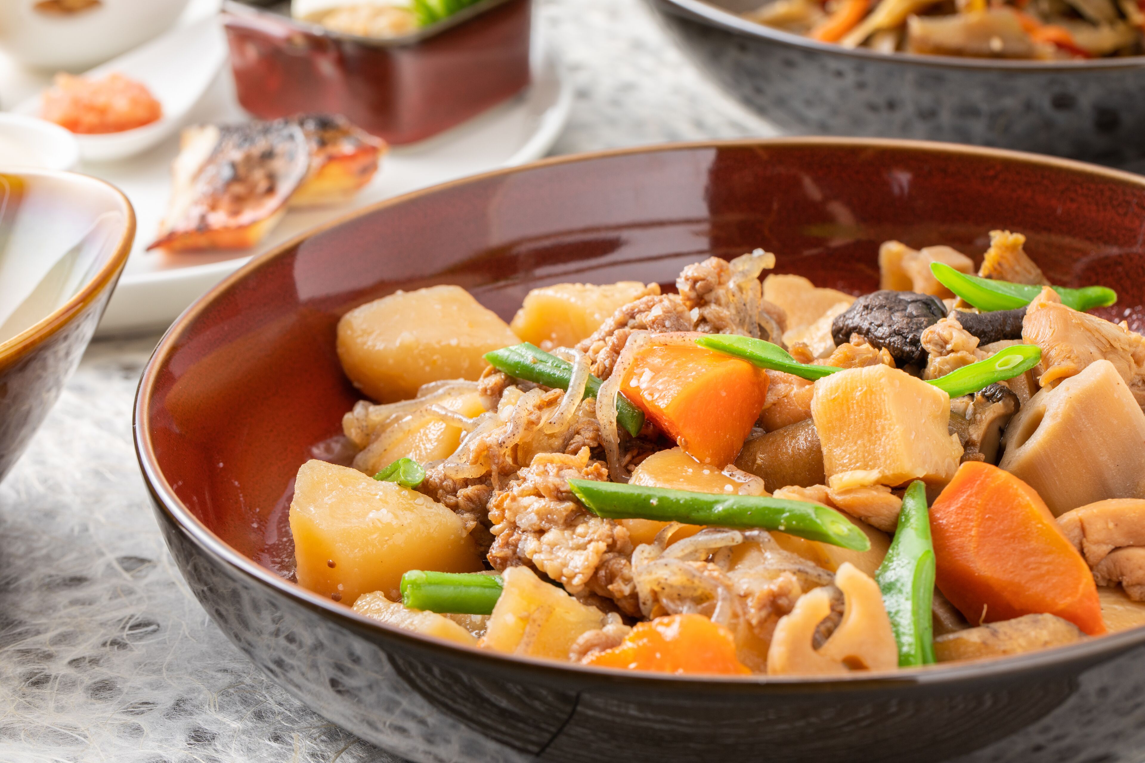 Uma tigela de ensopado com carne, batatas, cenouras e vagem.