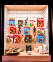 Exposição de cereais com diversos produtos Kellogg's e figuras de super-heróis.