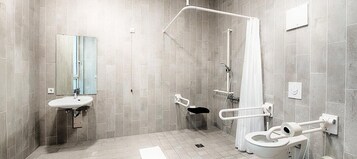 Uma casa de banho moderna com chuveiro, sanita e lavatório.