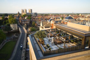 Terraço no telhado com assentos ao ar livre, vista da cidade e um edifício histórico ao fundo.