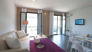 Uma sala de estar moderna com sofá, mesa de centro e área de jantar com cadeiras.