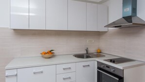 Uma cozinha moderna com armários brancos, uma pia de aço inoxidável e um forno embutido.