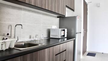 Uma cozinha moderna com uma pia de aço inoxidável, micro-ondas e armários de madeira.
