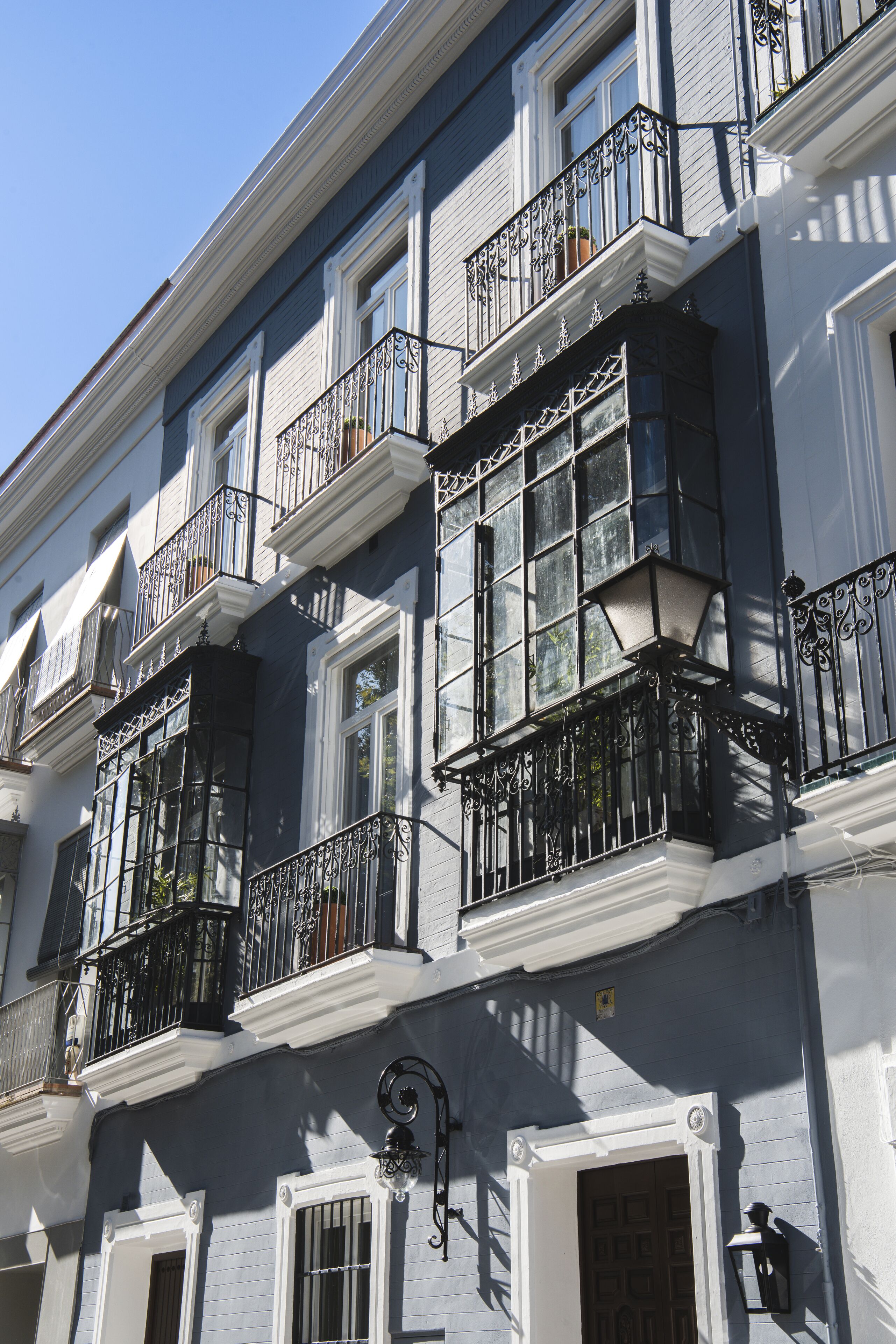 Um edifício com vários andares, janelas emolduradas por branco e varandas em ferro forjado preto.