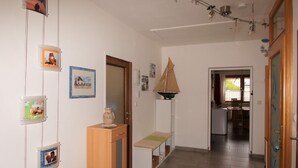 Um corredor com um armário de madeira, uma mesinha e um barco decorativo.