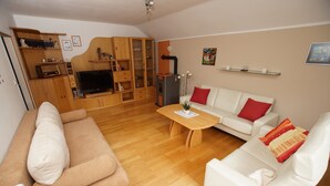 Uma sala de estar com sofá, mesa de centro, televisão, armários de madeira e lareira.