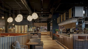 Uma área de bar moderna com assentos, balcão e luminárias pendentes.