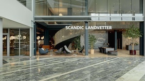 Um interior moderno com escada, área de estar e uma placa com a inscrição "SCANDIC LANDVETTER".