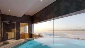 Quarto de hotel moderno com uma janela grande com vista para um aeroporto.
